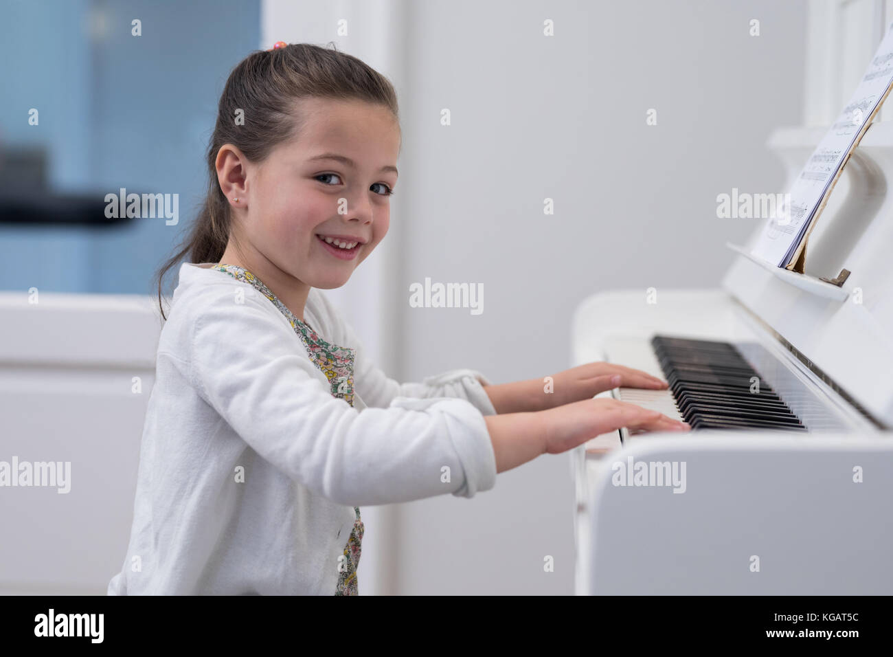 Portrait of cute girl playing piano at home Stock Photo - Alamy