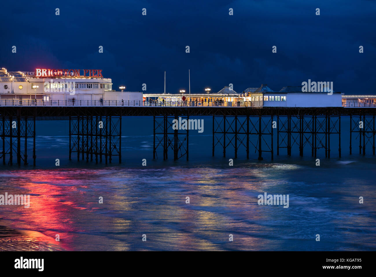 Brighton Pier, illuminated at night with dramatic dark sky and ...