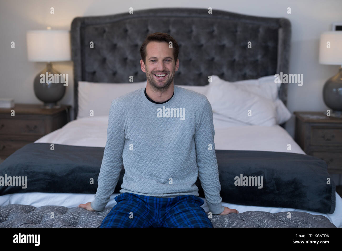 Portrait of happy man sitting on bed in bedroom Stock Photo - Alamy