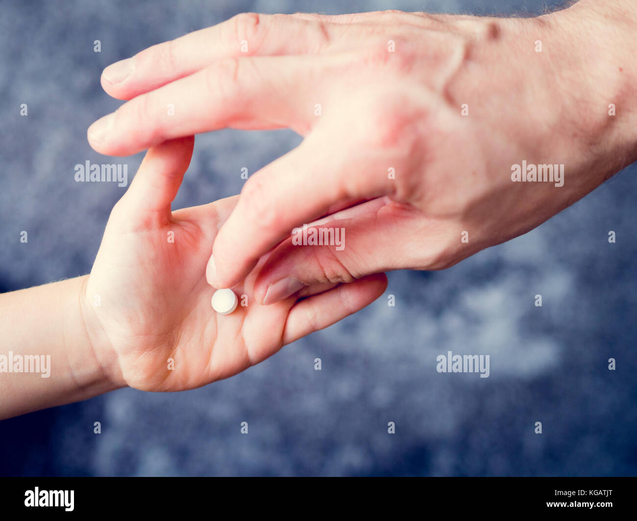 Close up of a hand of an adult giving pill, medicine, drug to a child ...