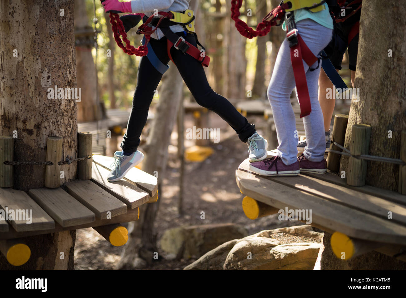 Low section of kids crossing zip line on a sunny day Stock Photo - Alamy
