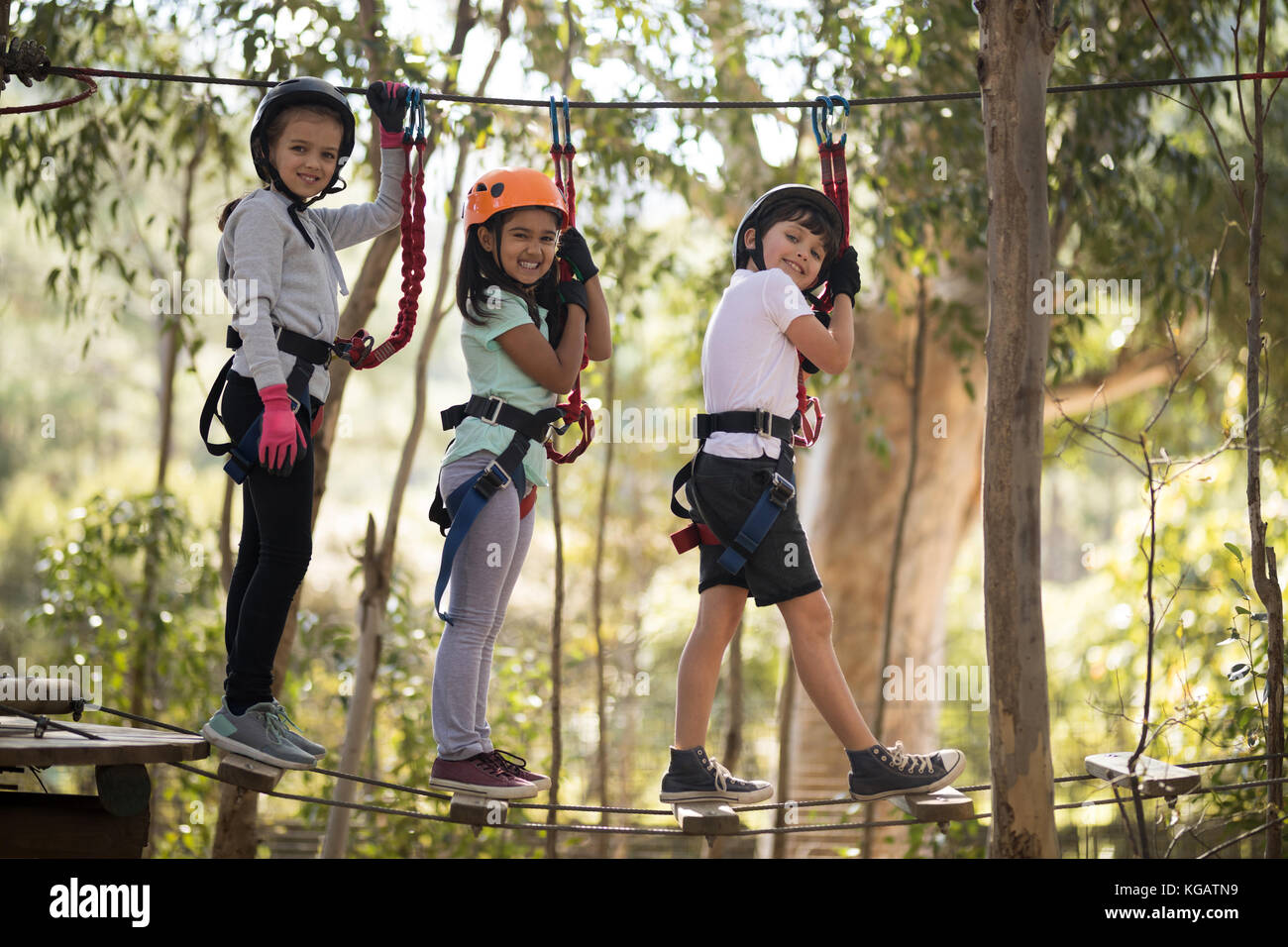 Portrait of happy kids crossing zip line on a sunny day Stock Photo - Alamy