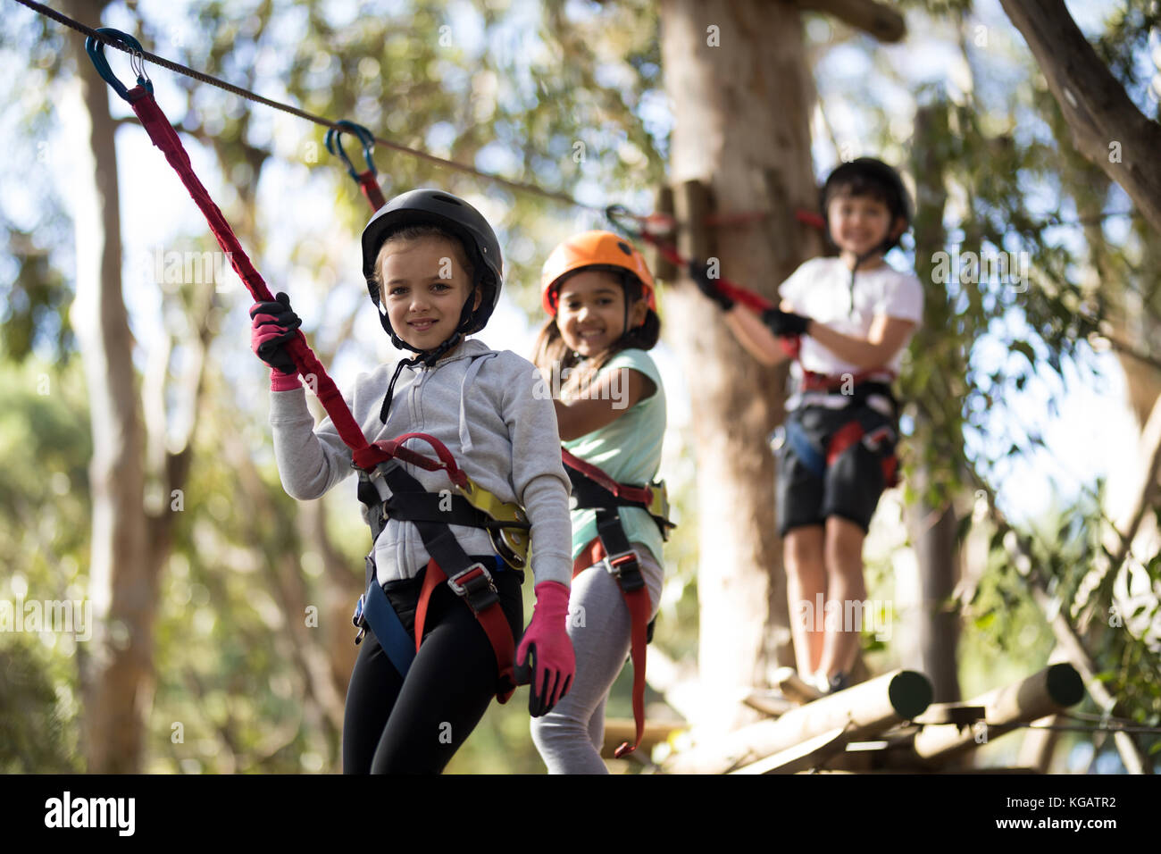 Portrait of happy kids crossing zip line on a sunny day Stock Photo - Alamy