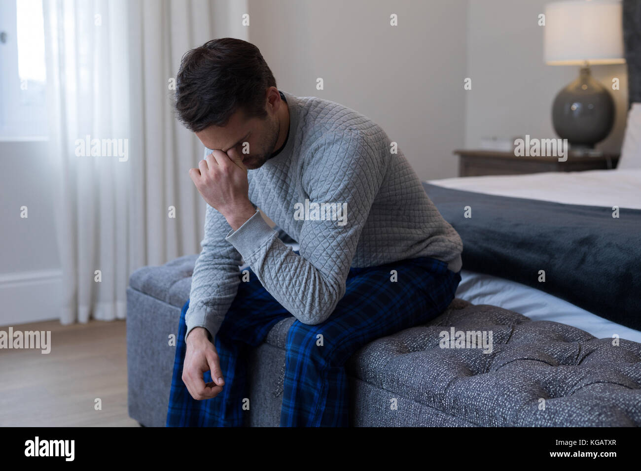 Tensed man sitting on bed in bedroom Stock Photo - Alamy