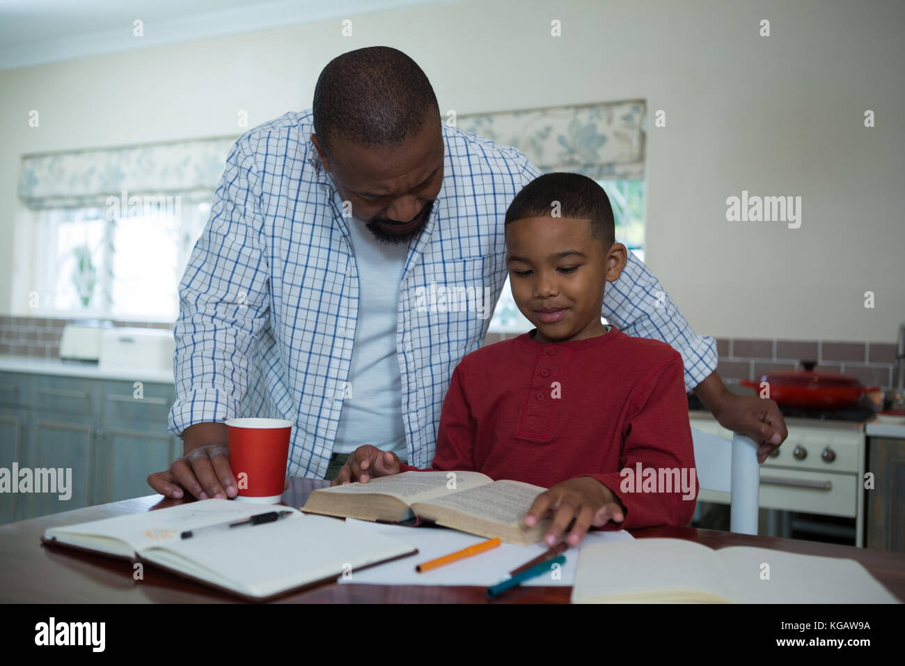 Father helping his son with homework in kitchen at home Stock Photo - Alamy