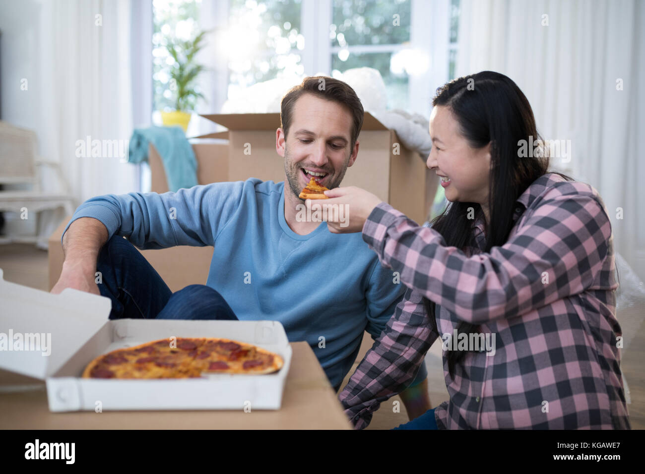 Happy couple having pizza at their new home Stock Photo - Alamy