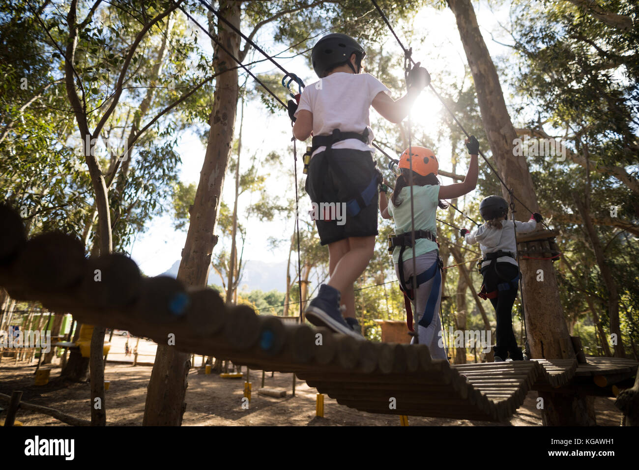 Determined kids crossing zip line on a sunny day Stock Photo - Alamy