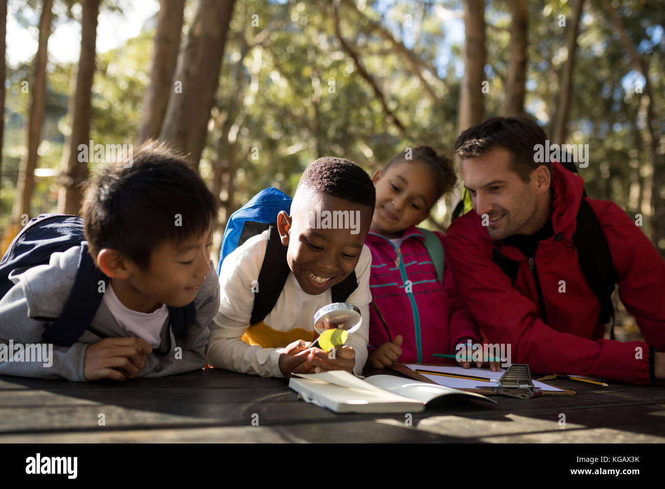 Teacher assisting kids in studying at park Stock Photo - Alamy