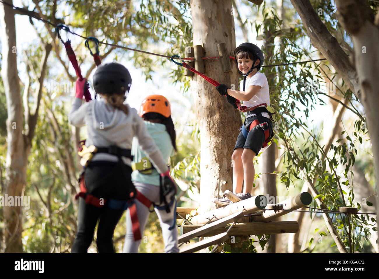 Determined kids crossing zip line on a sunny day Stock Photo - Alamy