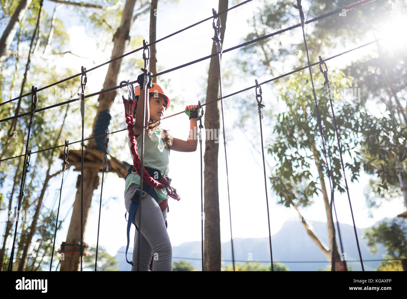 Determined girl crossing zip line on a sunny day Stock Photo - Alamy