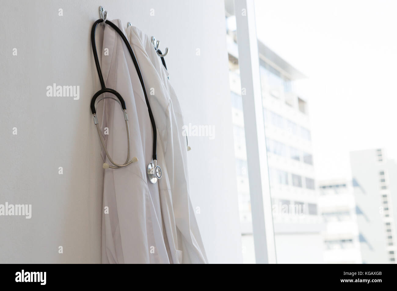 Laboratory coat and stethoscope hanging on hook against wall Stock ...