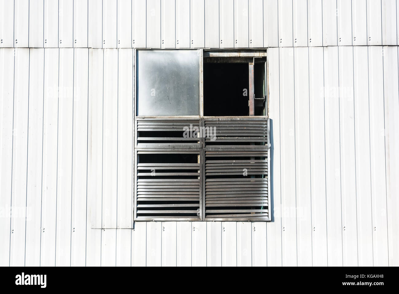 Close up white wall of factory building with small old window with ...