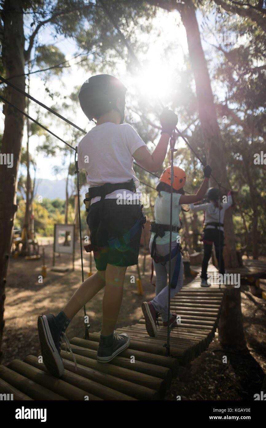 Determined kids crossing zip line on a sunny day Stock Photo - Alamy