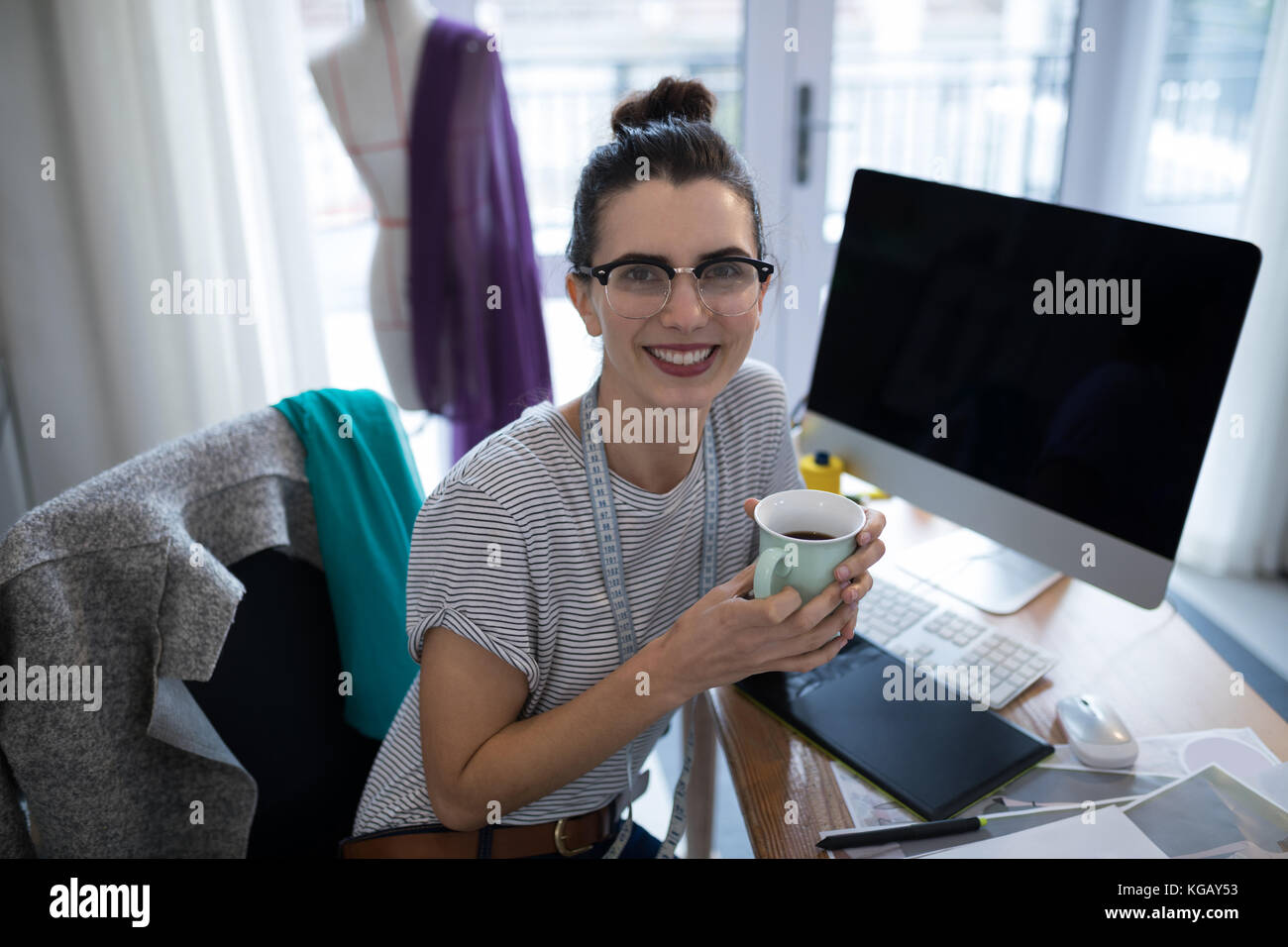 Portrait of smiling female designer having coffee at desk Stock Photo ...