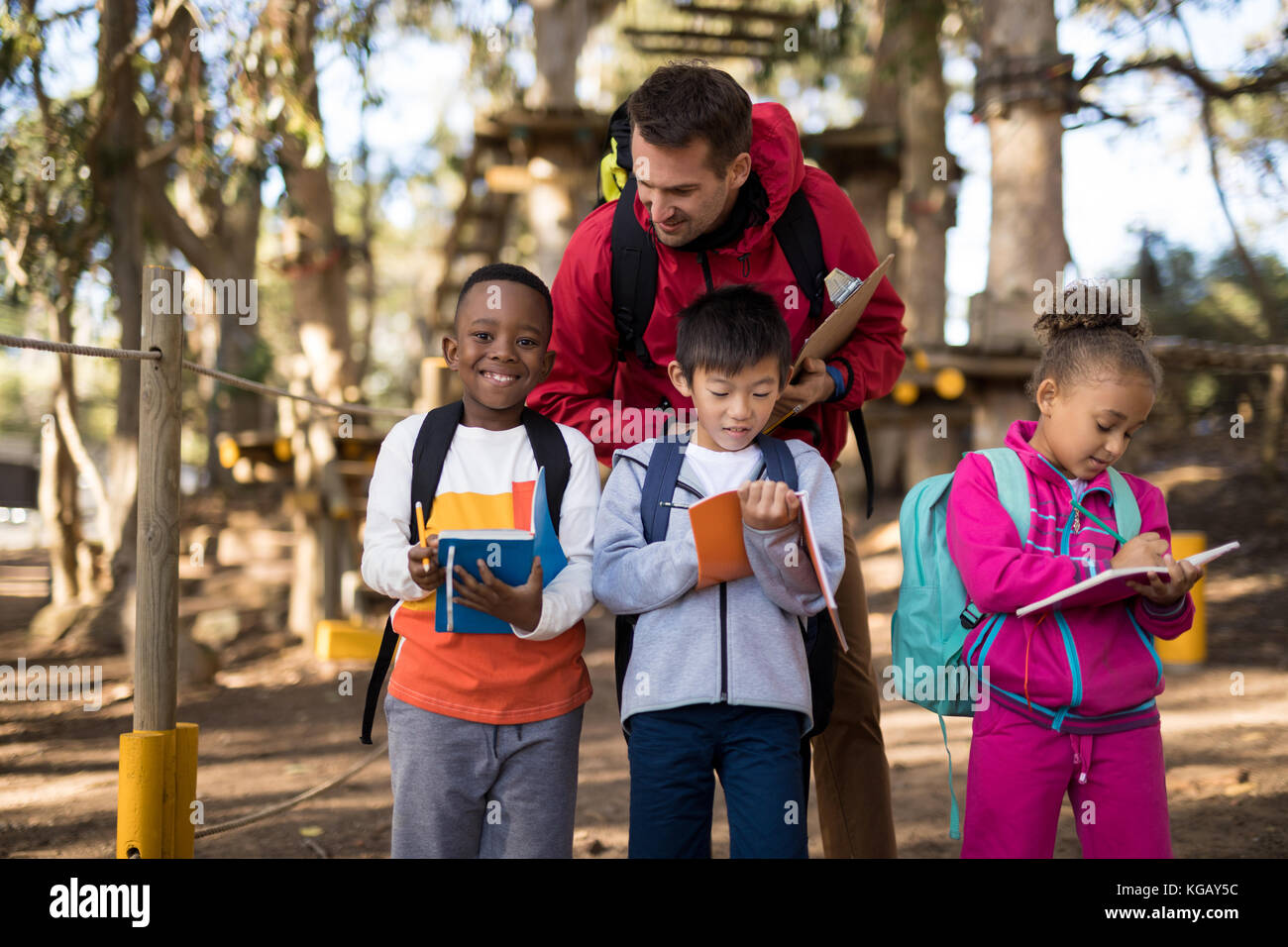 Teacher assisting kids in studying at park Stock Photo - Alamy