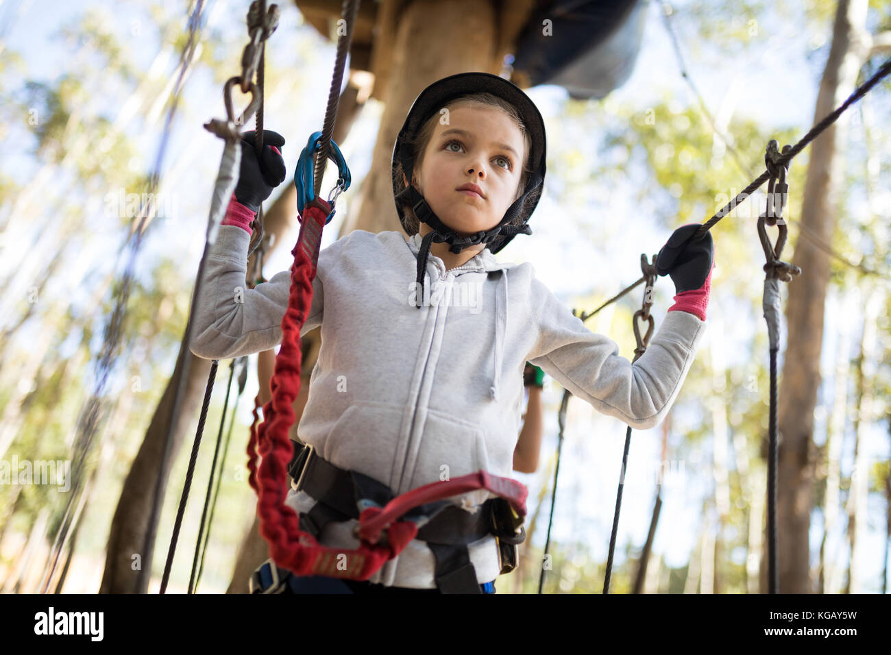 Determined girl crossing zip line on a sunny day Stock Photo - Alamy