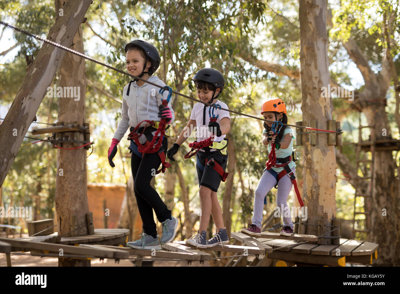 Determined kids crossing zip line on a sunny day Stock Photo - Alamy