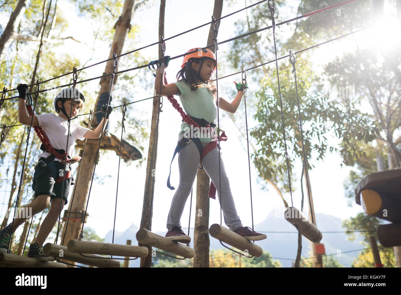 Determined kids crossing zip line on a sunny day Stock Photo - Alamy