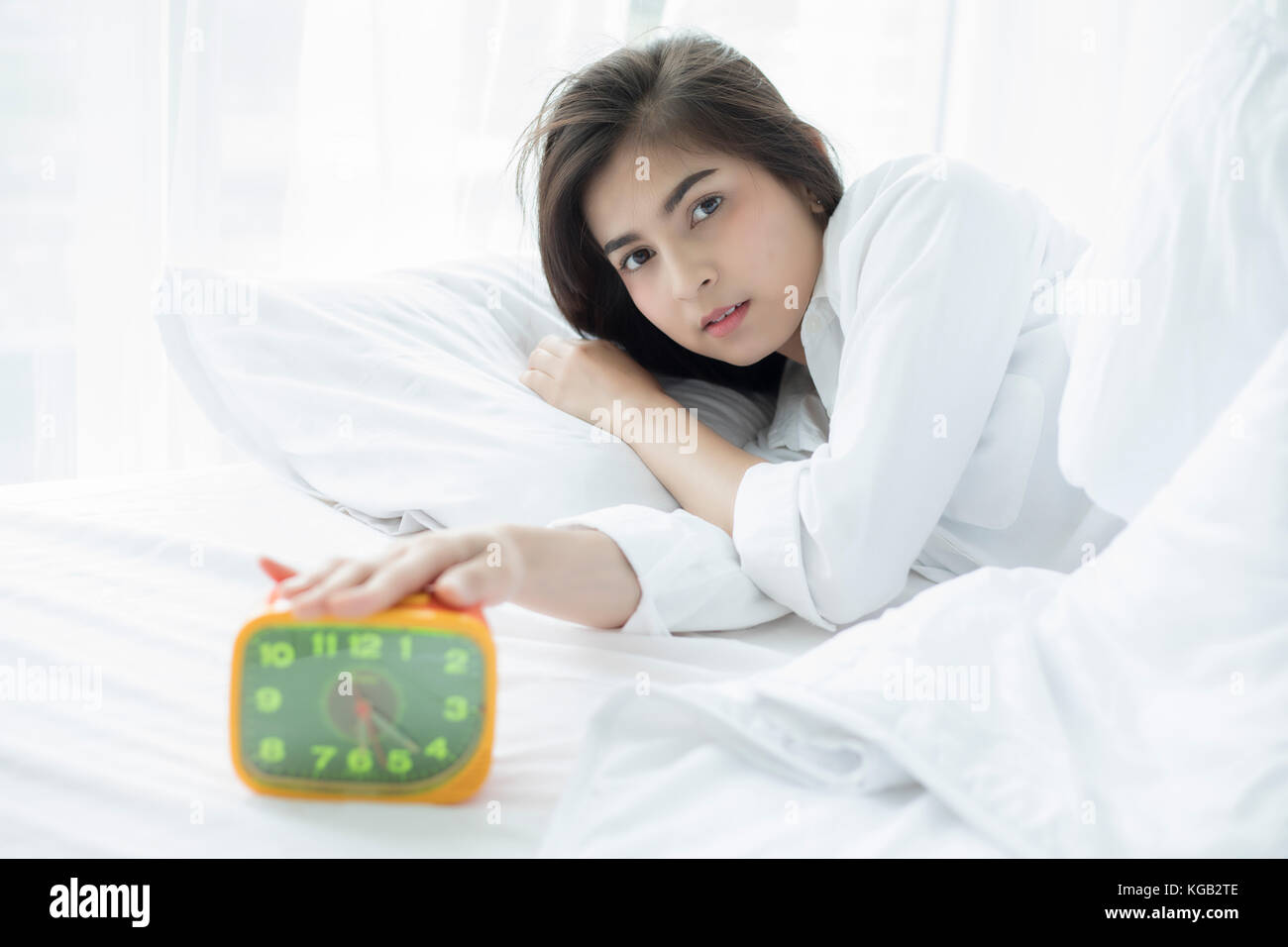asian woman happy waking up and turning off the alarm clock having a ...