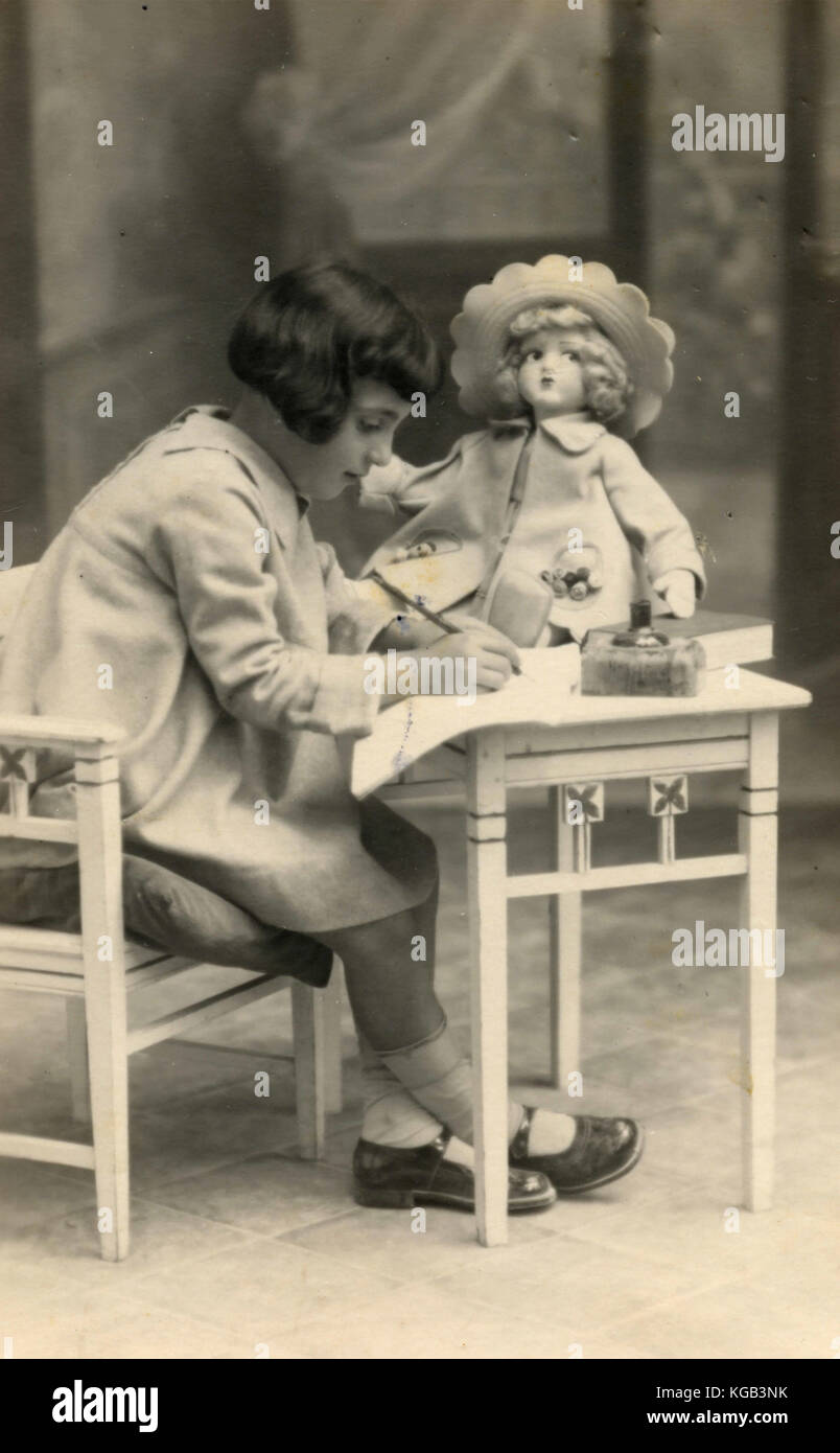 Girl writing and doll, 1920s Stock Photo - Alamy