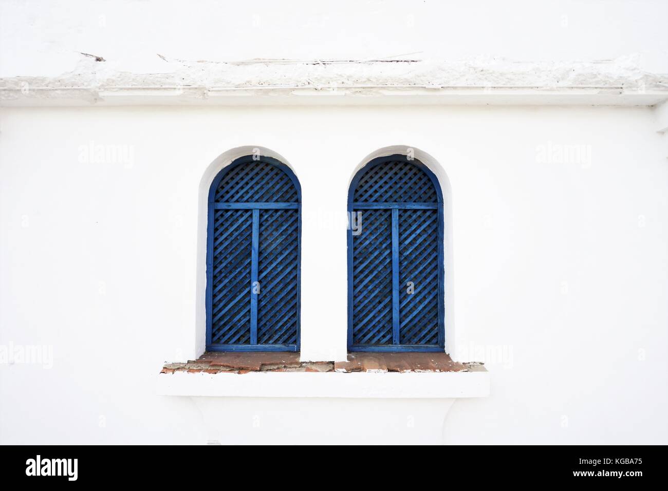 Two blue wooden windows in white house Stock Photo - Alamy