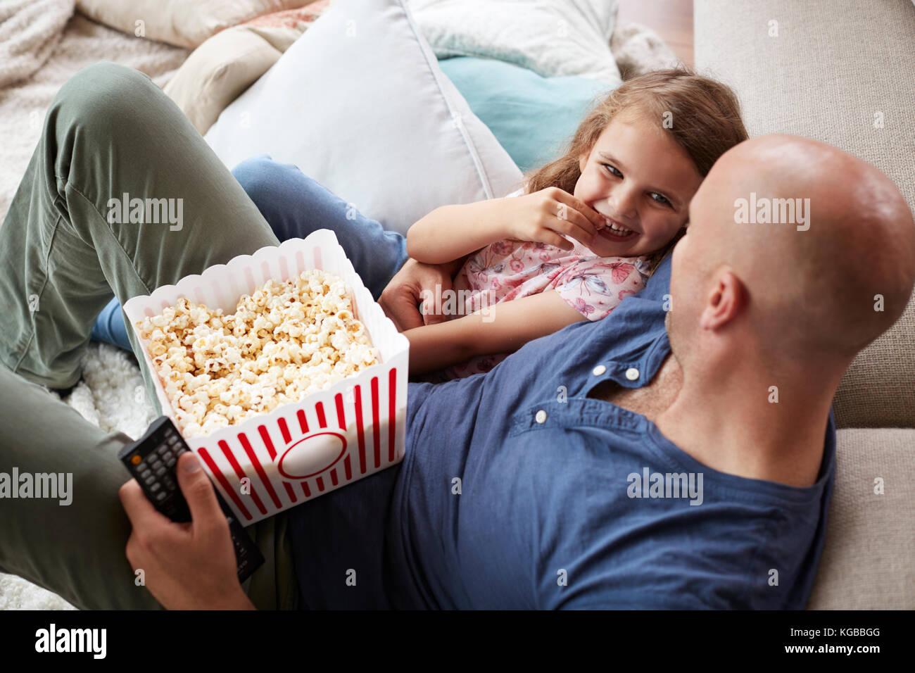 Dad and daughter eating popcorn at home, elevated side view Stock Photo ...