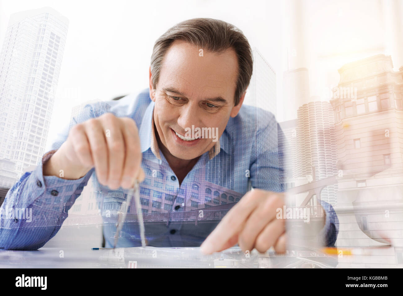 Joyful senior engineer drawing a blueprint with compasses Stock Photo ...
