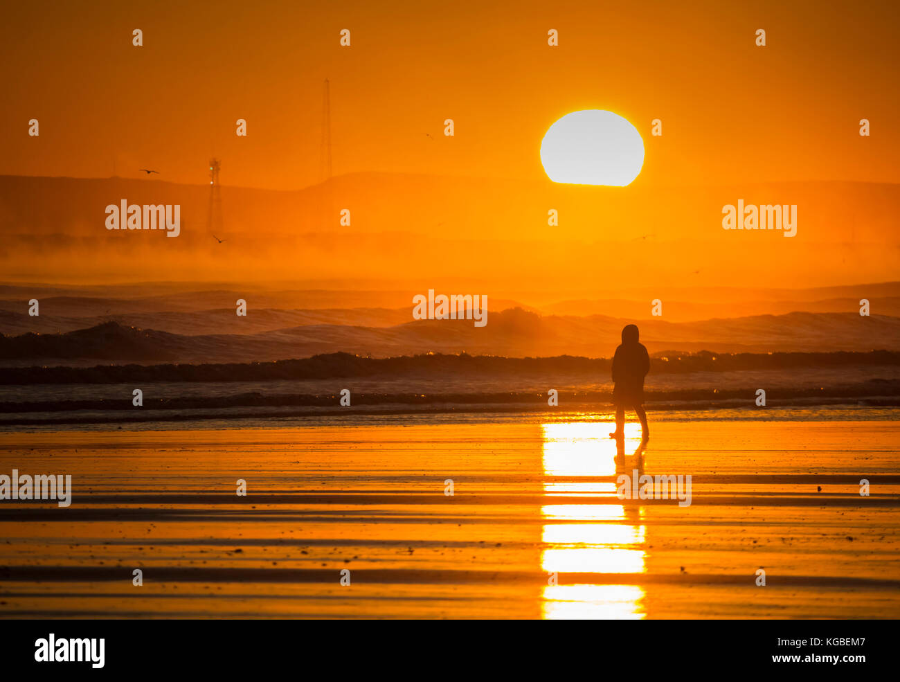 Person walking on beach at sunrise Stock Photo - Alamy