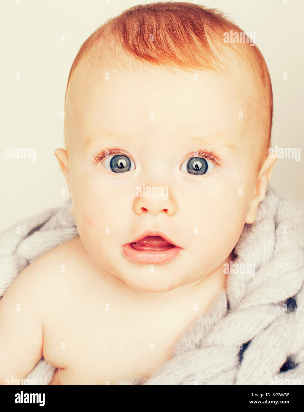 little cute red head baby in scarf all over him close up isolate Stock ...