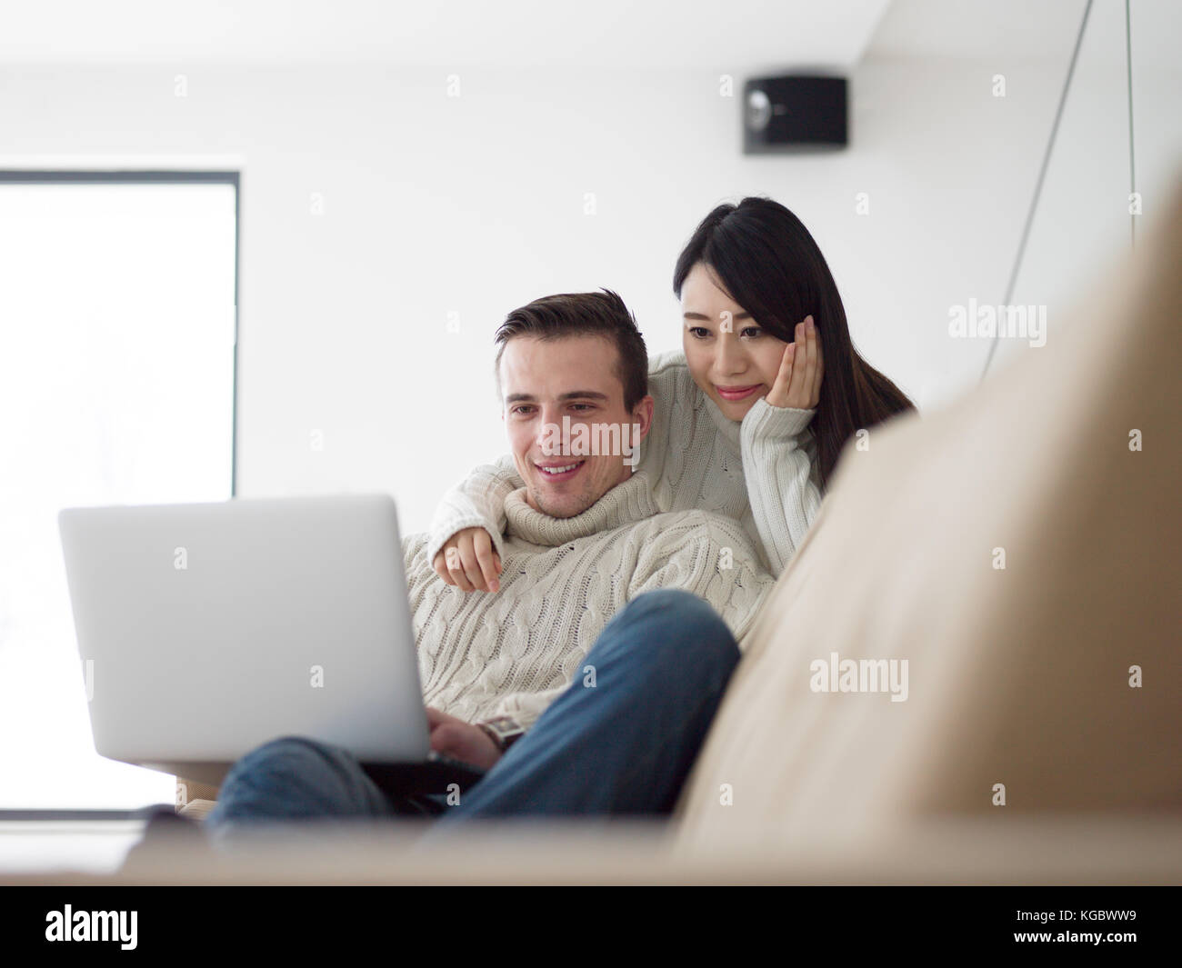 Young multiethnic couple relaxing at luxury home using laptop computer ...