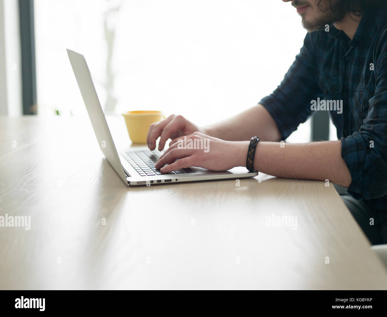 young man drinking coffee while working from home on his laptop ...