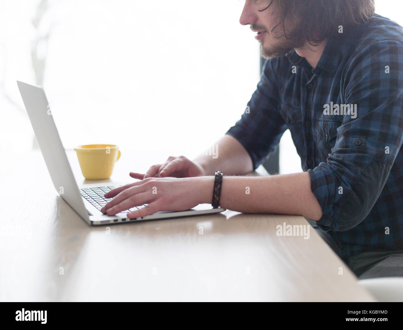young man drinking coffee while working from home on his laptop ...