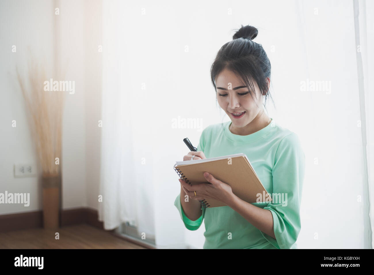 Lifestyle scene of young attractive Asian woman writing journal on ...