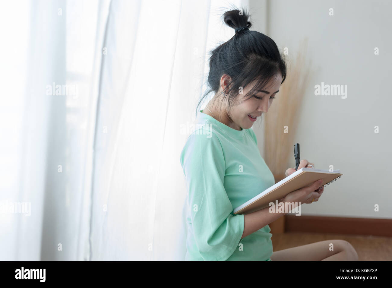 Lifestyle scene of young attractive Asian woman writing journal on ...