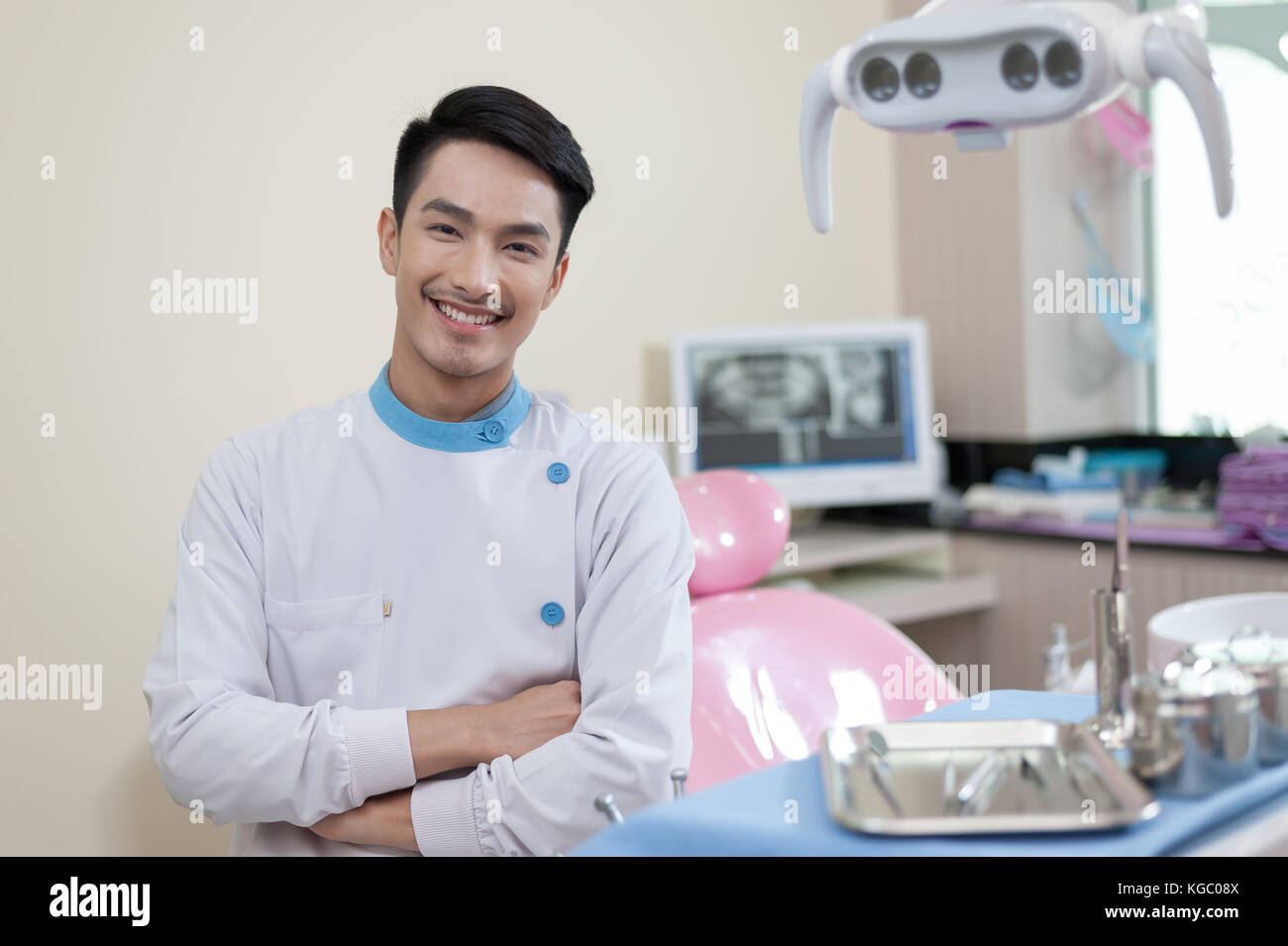 Male dentist crossing arm while standing in front of dental equipments ...