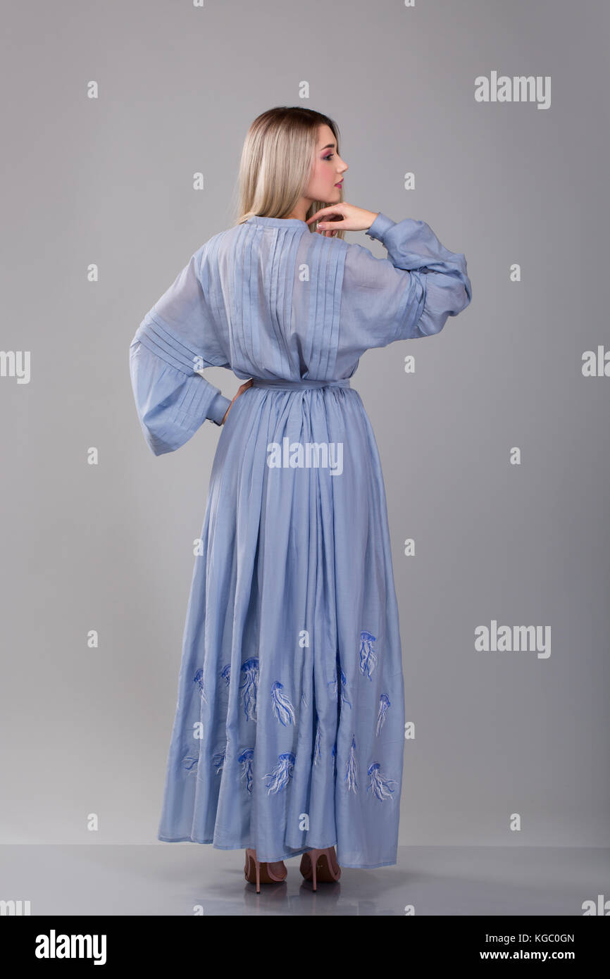 Woman in a long blue dress on gray background. back view Stock Photo ...