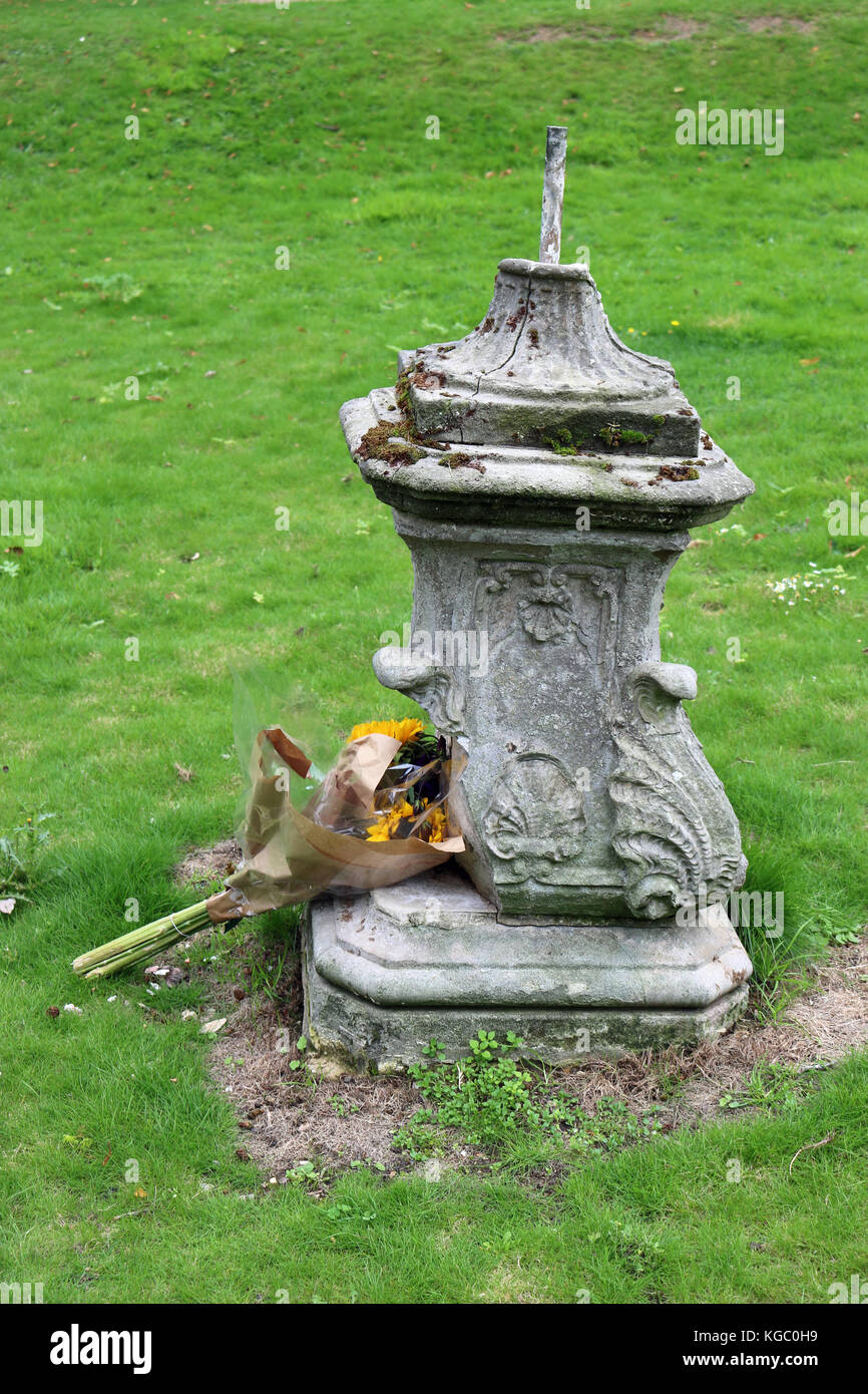 Damaged park stone ornamental jardiniere base with wilting flower ...