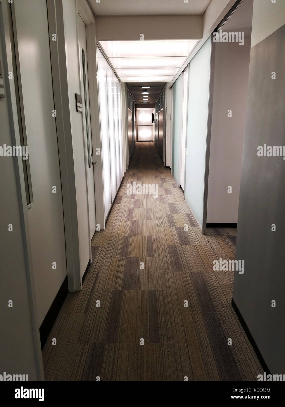 A long, dimly-lit white hallway Stock Photo - Alamy