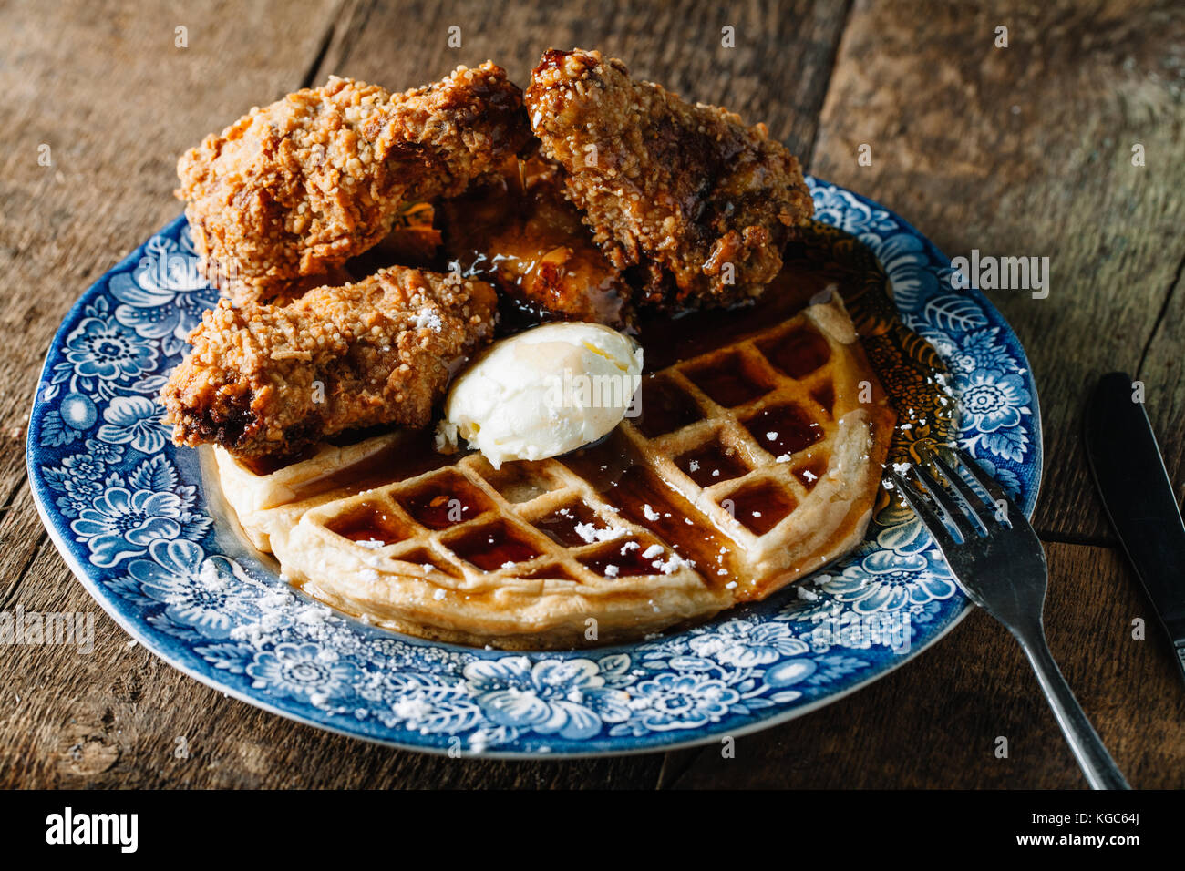 Chicken wings and waffles served with butter on blue vintage plate ...