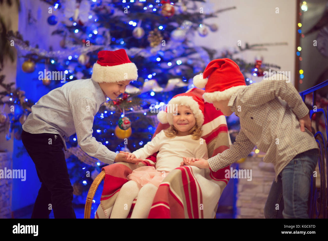 Portrait of three happy children having fun at Christmas eve at home ...