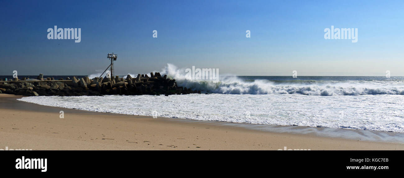 Large waves crash against this jetty with its navigational beacon the ...