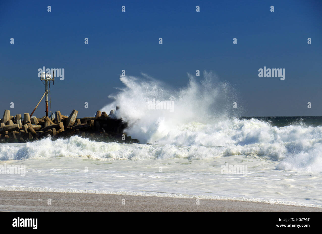 Large waves crash against this jetty with its navigational beacon the ...