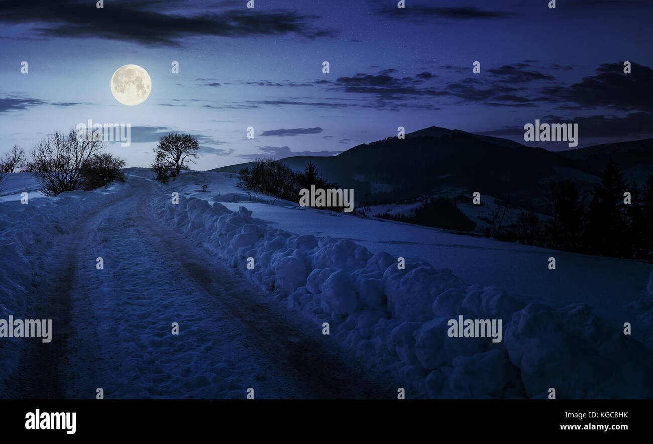 countryside road uphill in snow at night in full moon light. beautiful ...