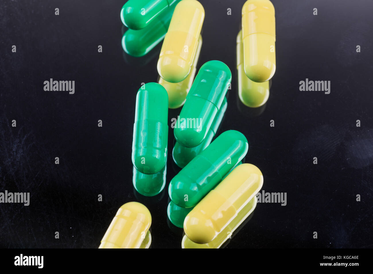 yellow and green capsules medications on a mirrored background Stock ...
