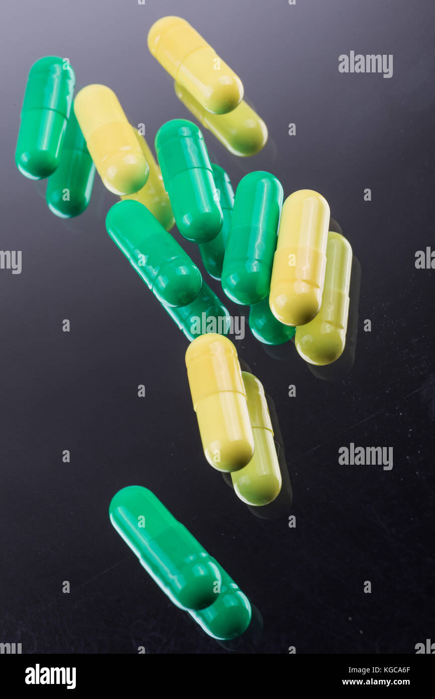 yellow and green capsules medications on a mirrored background Stock ...