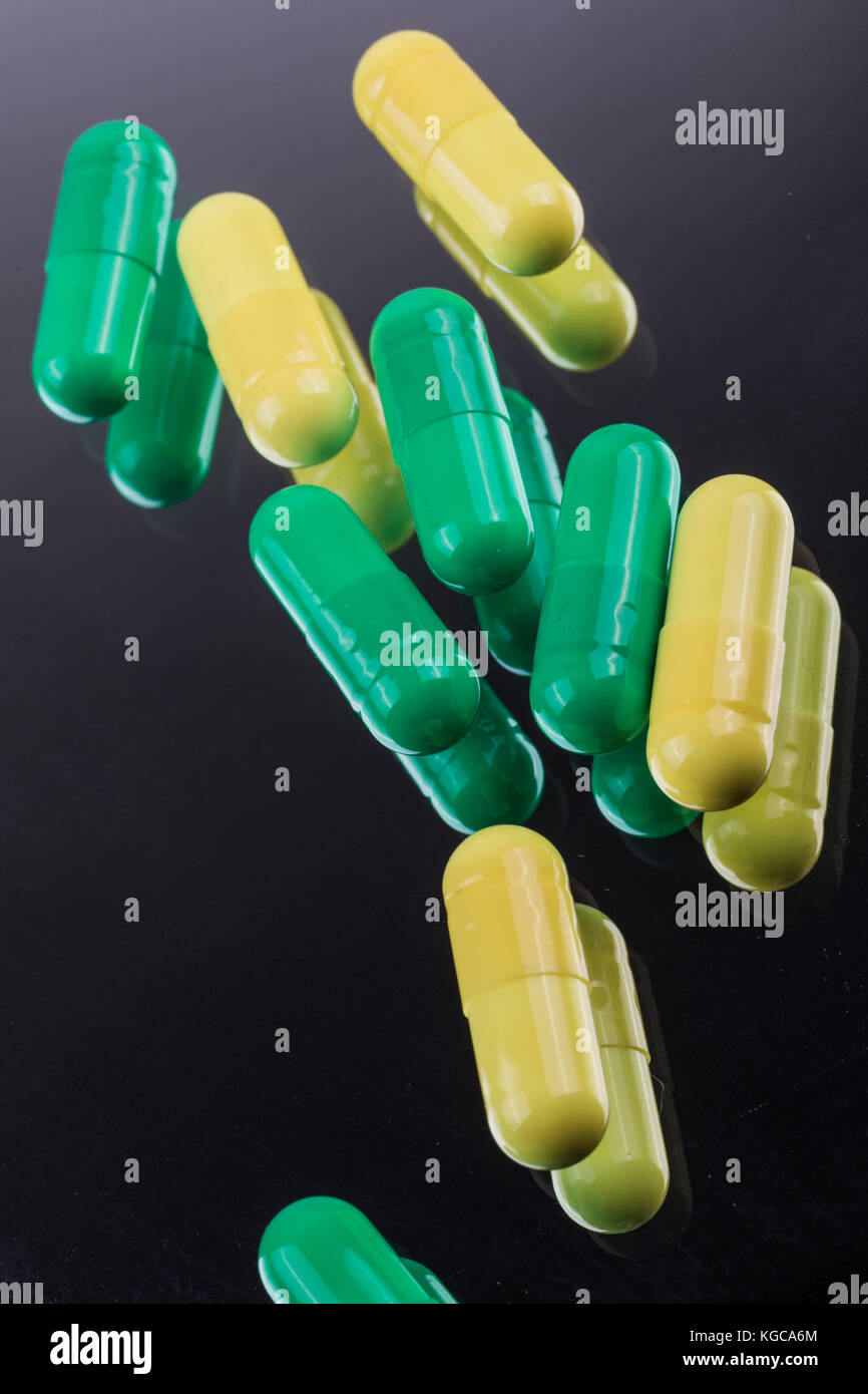 yellow and green capsules medications on a mirrored background Stock ...