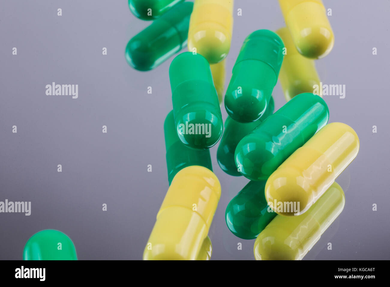yellow and green capsules medications on a mirrored background Stock ...