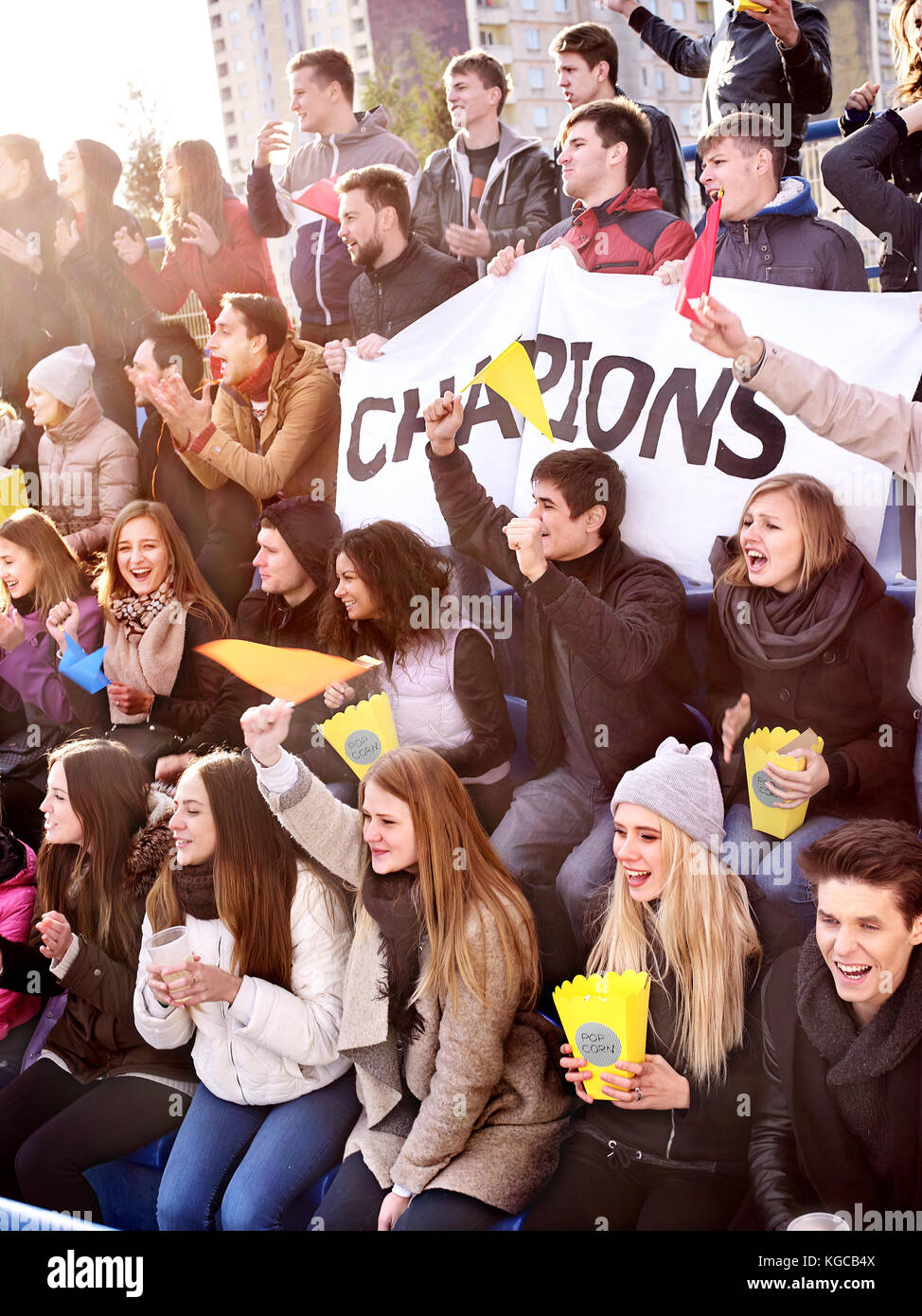Fans cheering in stadium and eating popcorn in yellow boxes and drink ...