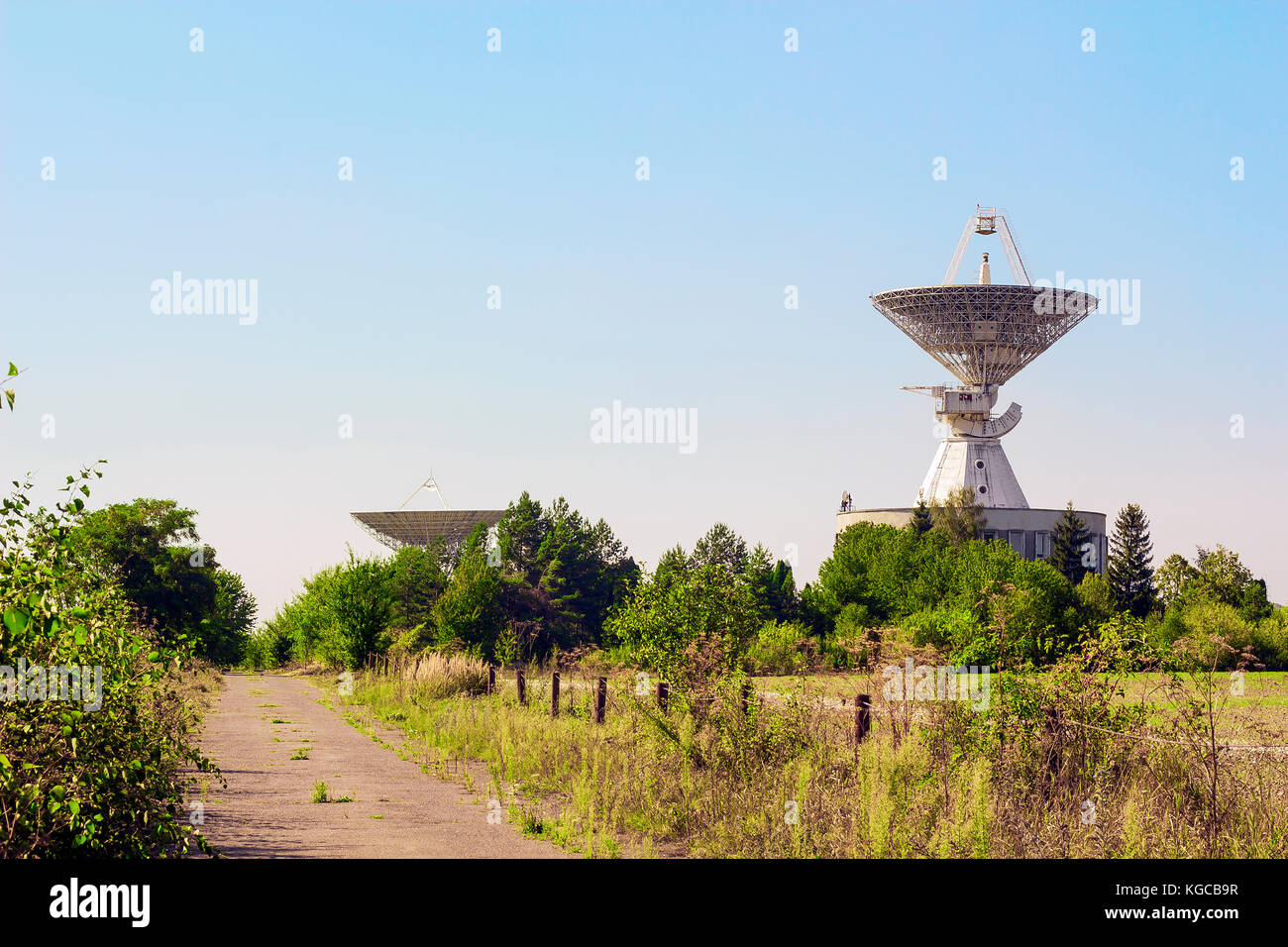 Large satellite dish radar antenna station in field against blue sky ...
