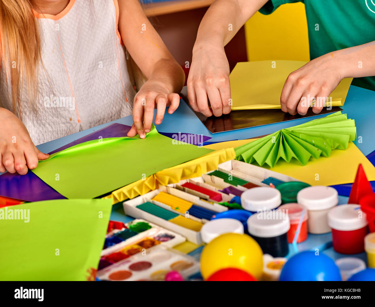 School children with scissors in kids hands cutting paper with teacher ...